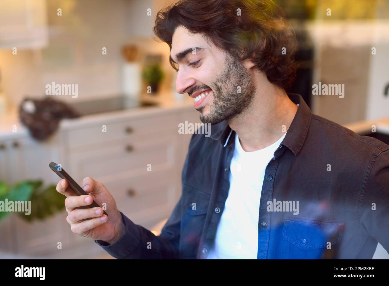 Man Relaxing At Home In Kitchen Checking Messages Social Media On ...
