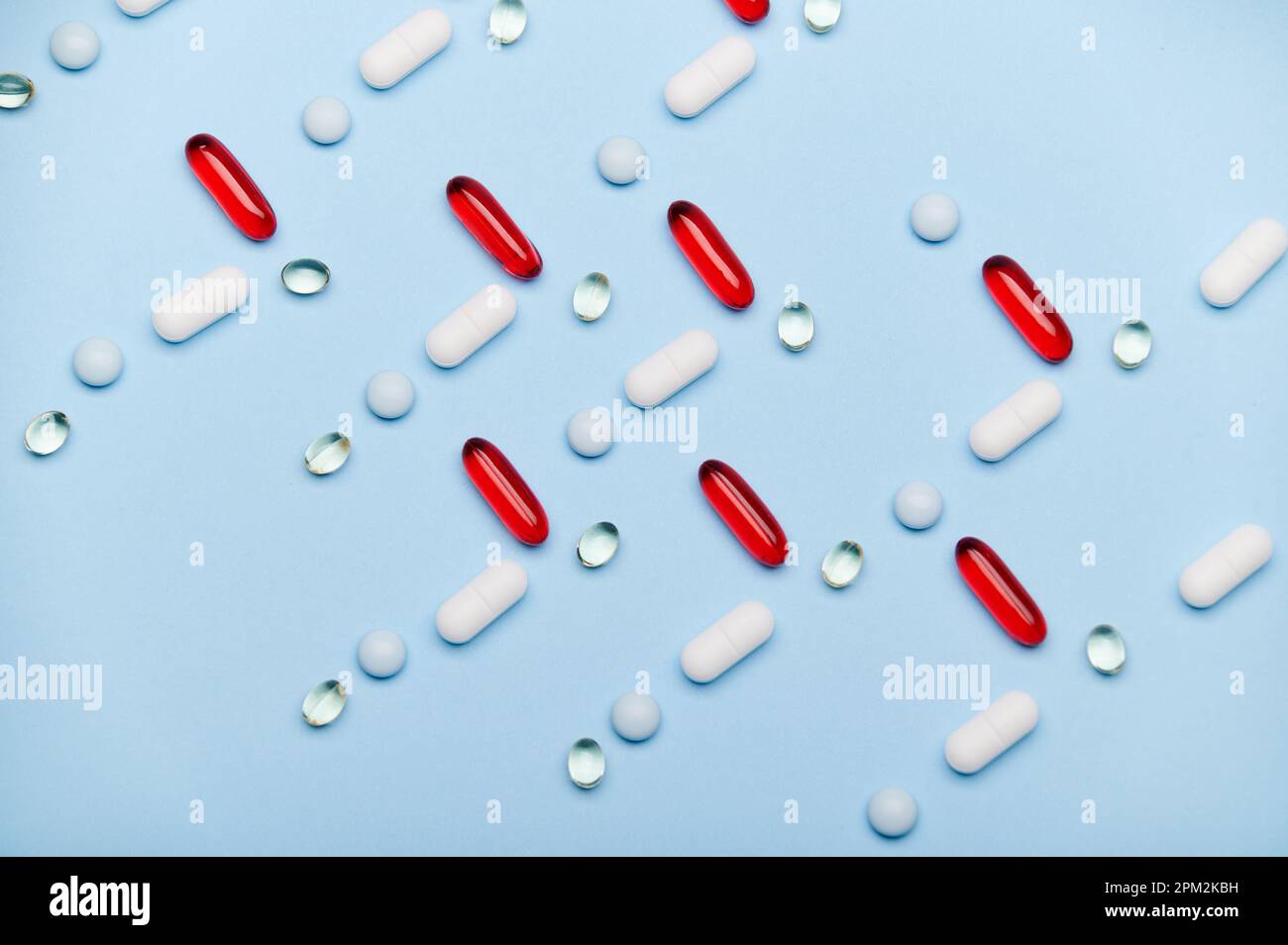 Flat lay. Red gel translucent capsules, dragees, medical pills arranged ...