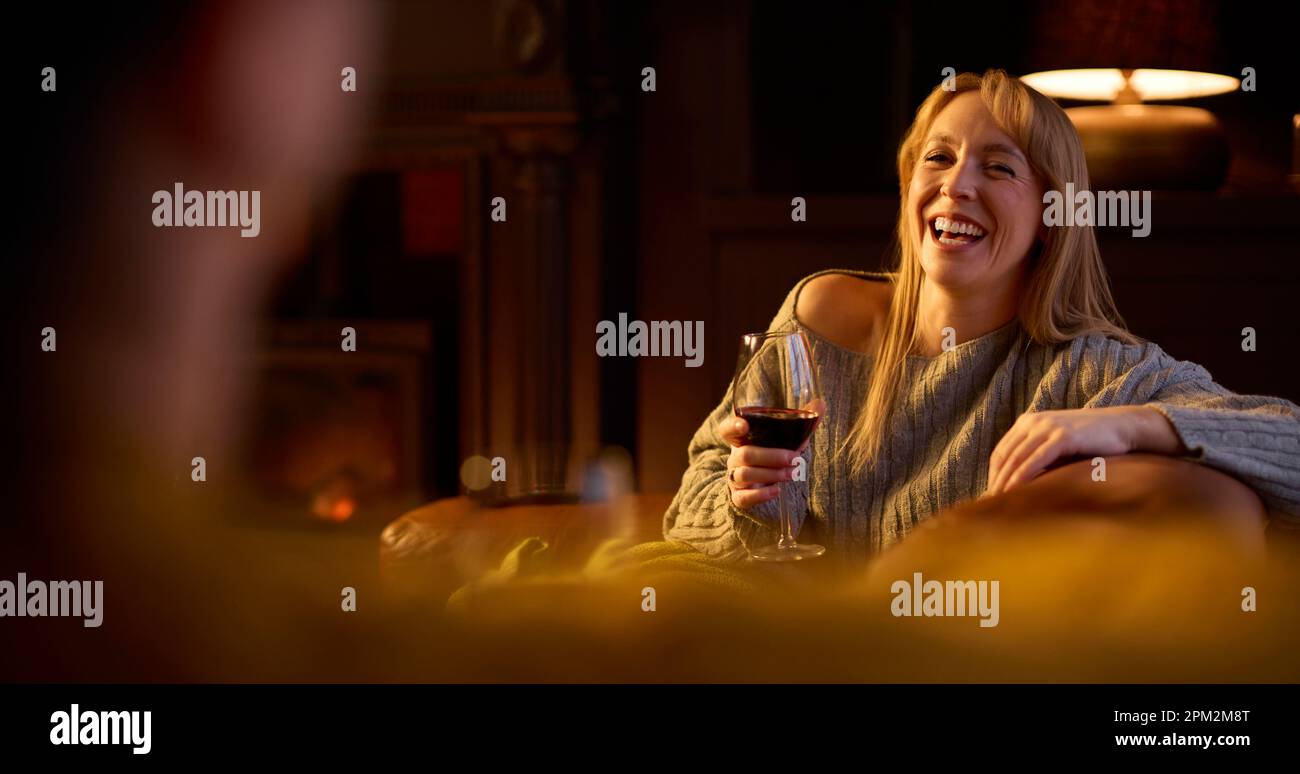 Two Female Friends Relaxing And Laughing On Sofa In Lounge With Cosy ...