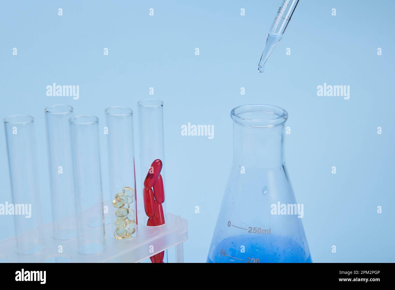 Focus on drops with blue solution dripping from a graduated pipette ...