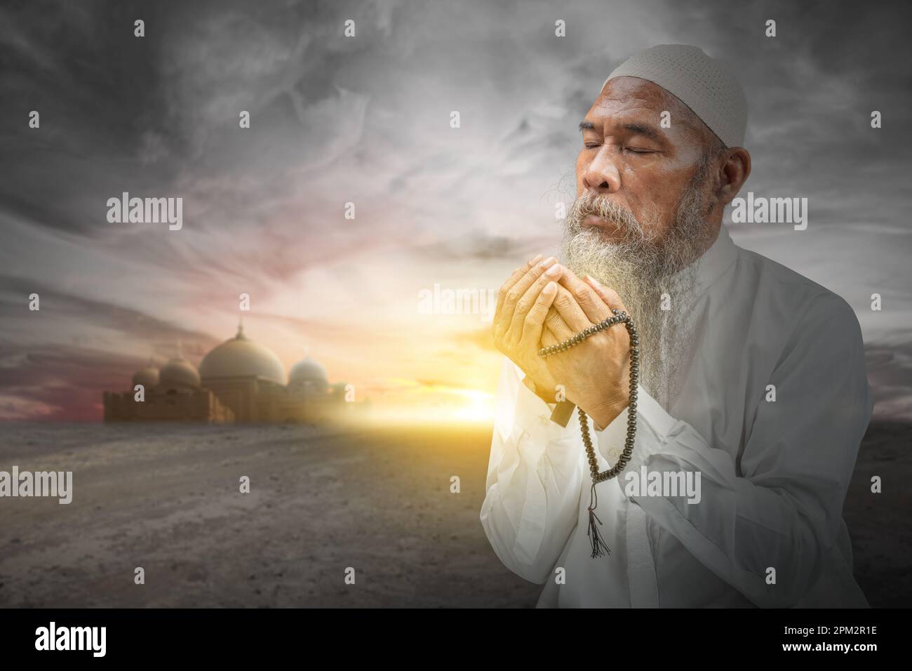 Muslim man with a beard wearing a white cap praying with prayer beads ...