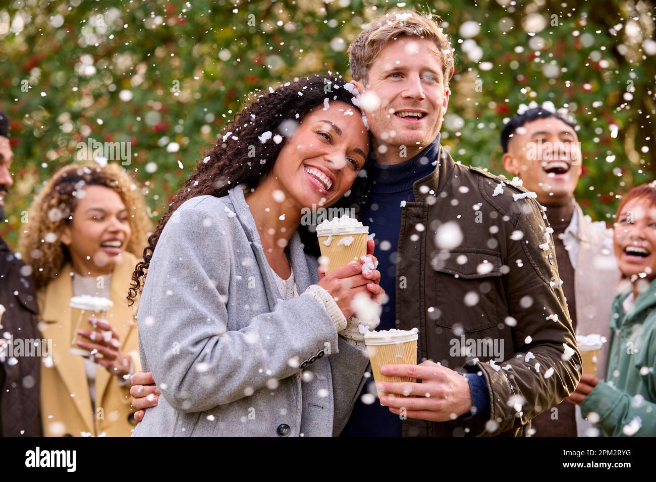 Group Of Friends Wearing Coats Standing Outside In Snow Holding ...