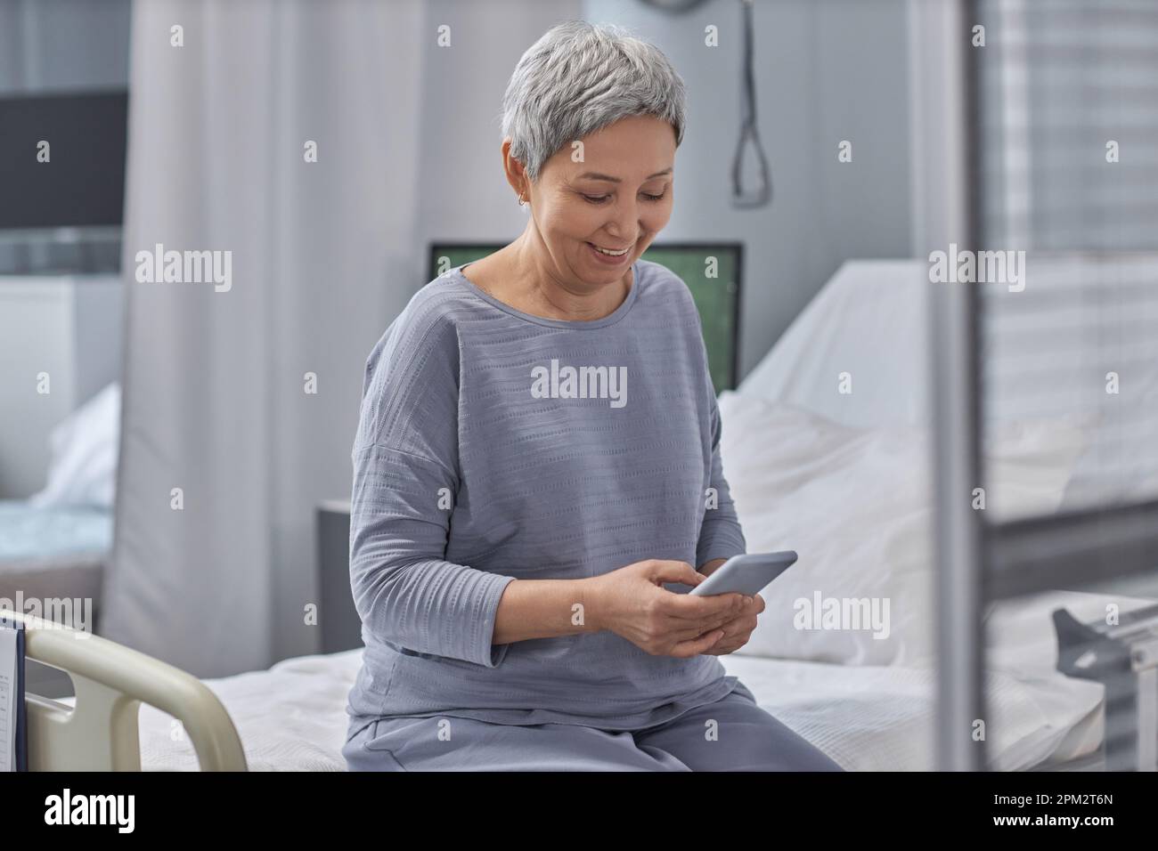 Senior patient reading message on her mobile phone and smiling while ...