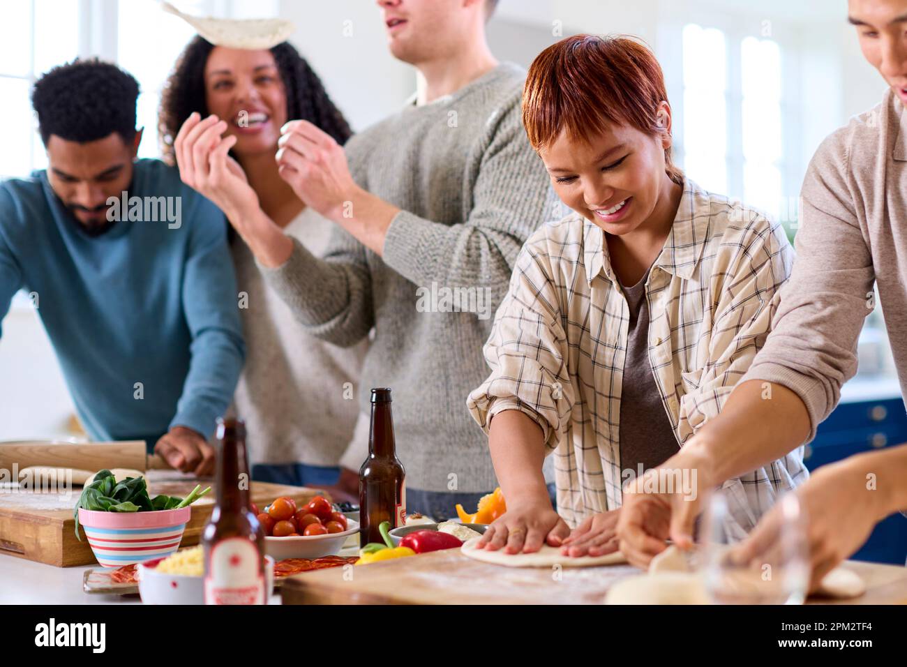 Group Of Friends At Home In Kitchen With Making Pizzas For Party ...