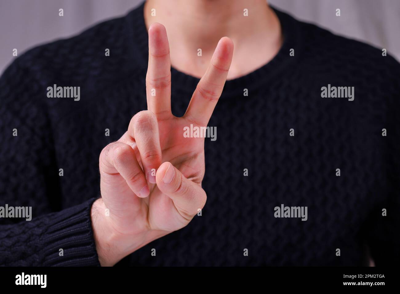 Young man holding two fingers up showing peacekeeping struggle or ...