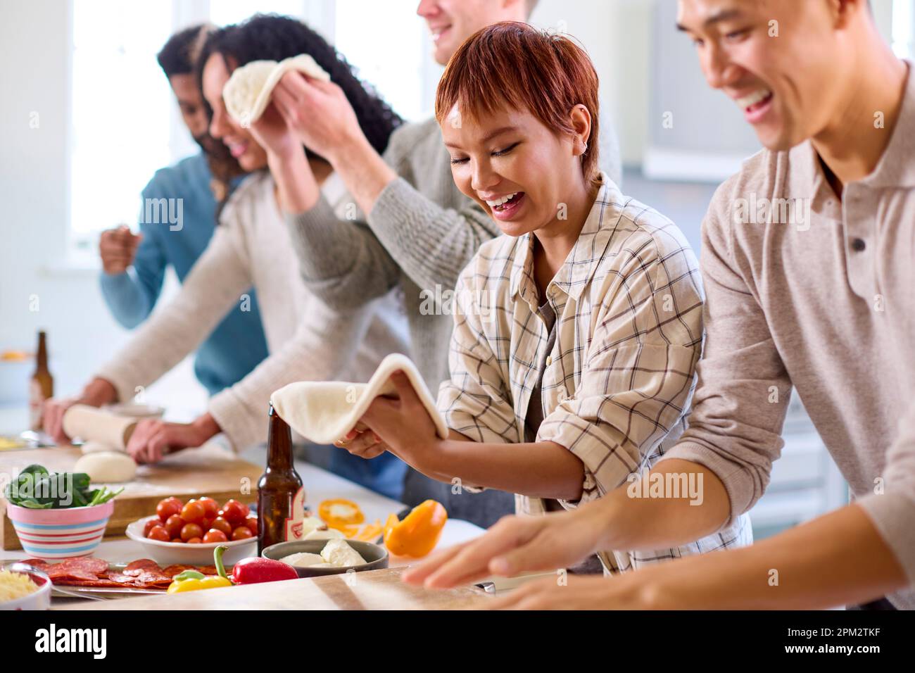 Group Of Friends At Home In Kitchen With Making Pizzas For Party ...