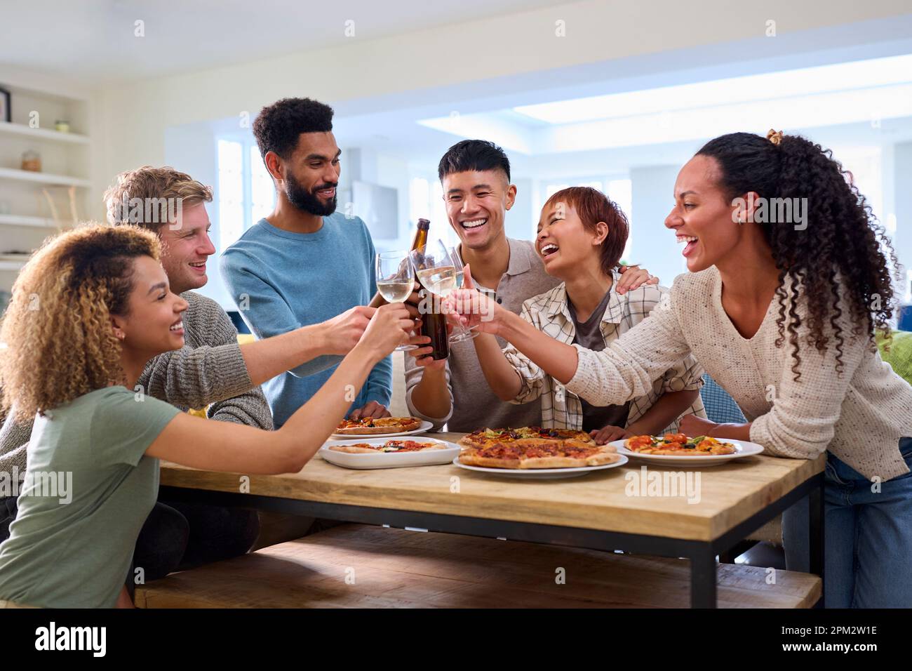 Friends Celebrating With Cheers At Home In Kitchen Eating Homemade ...