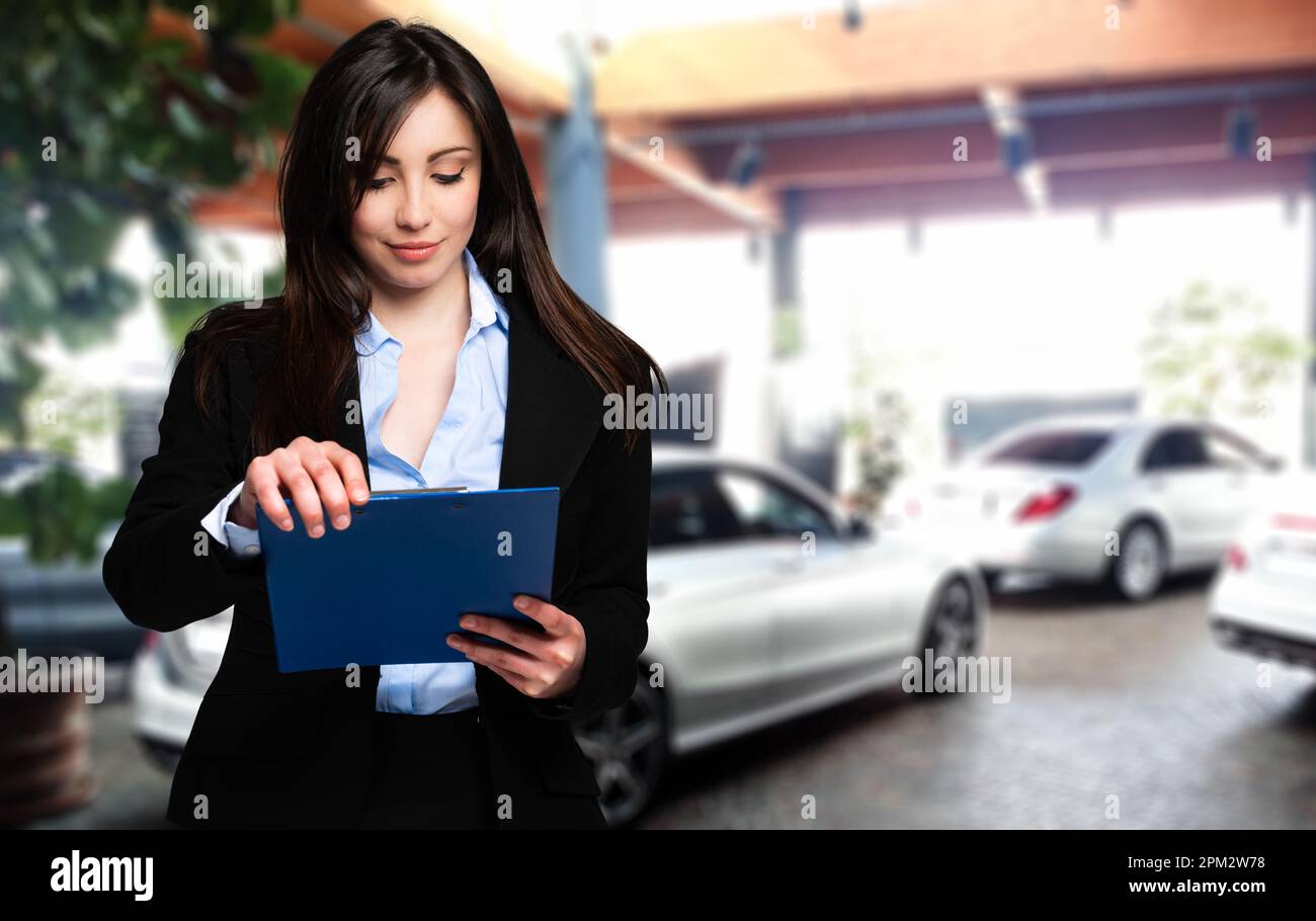 Beautiful car dealer reading a contract Stock Photo - Alamy