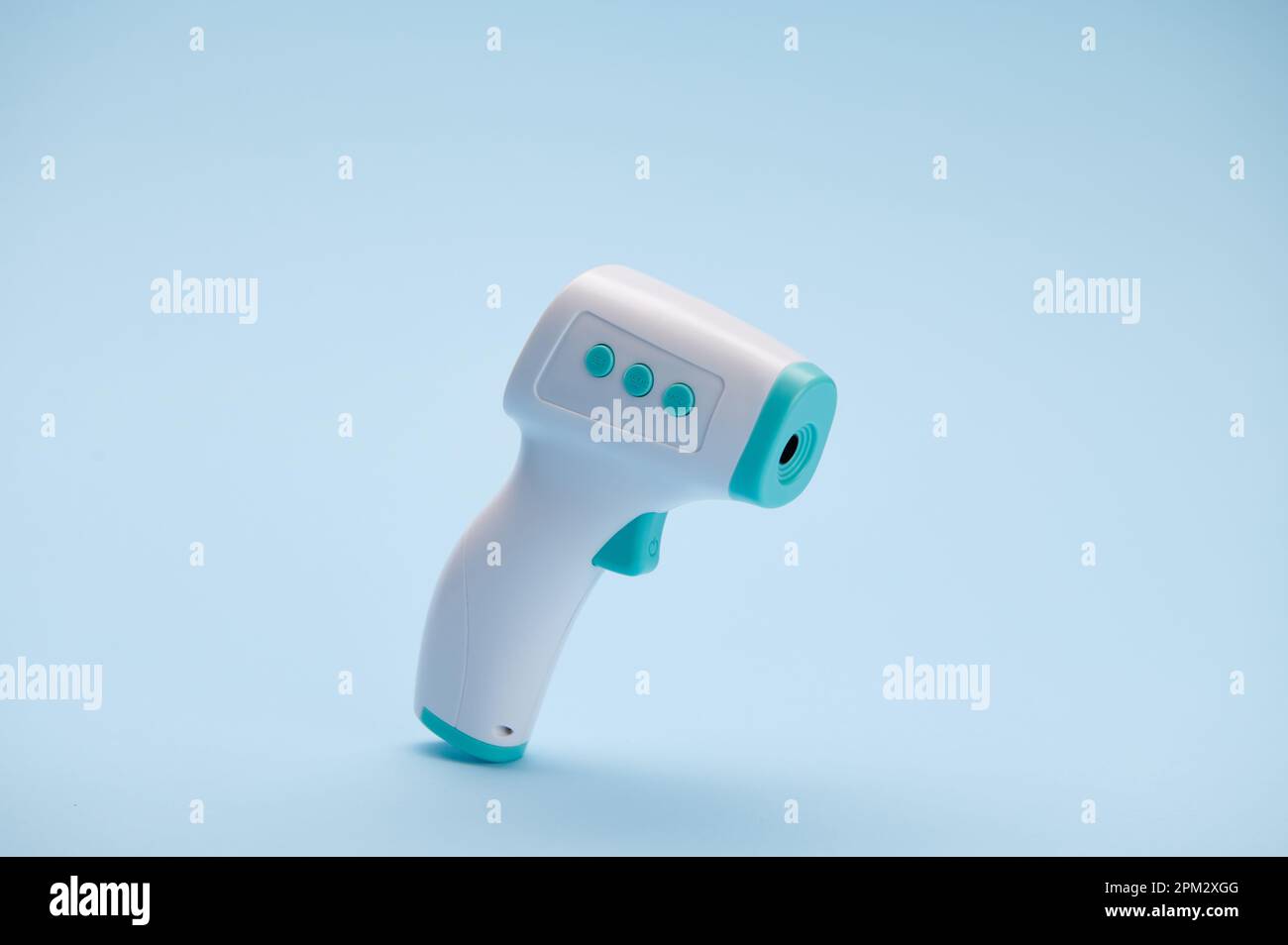 Infrared electronic thermometer gun on a blue background. Copy ad space ...