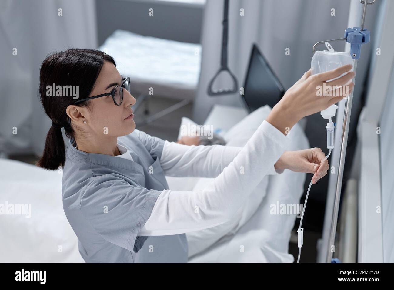 High angle view of young nurse making drip for senior patient while ...