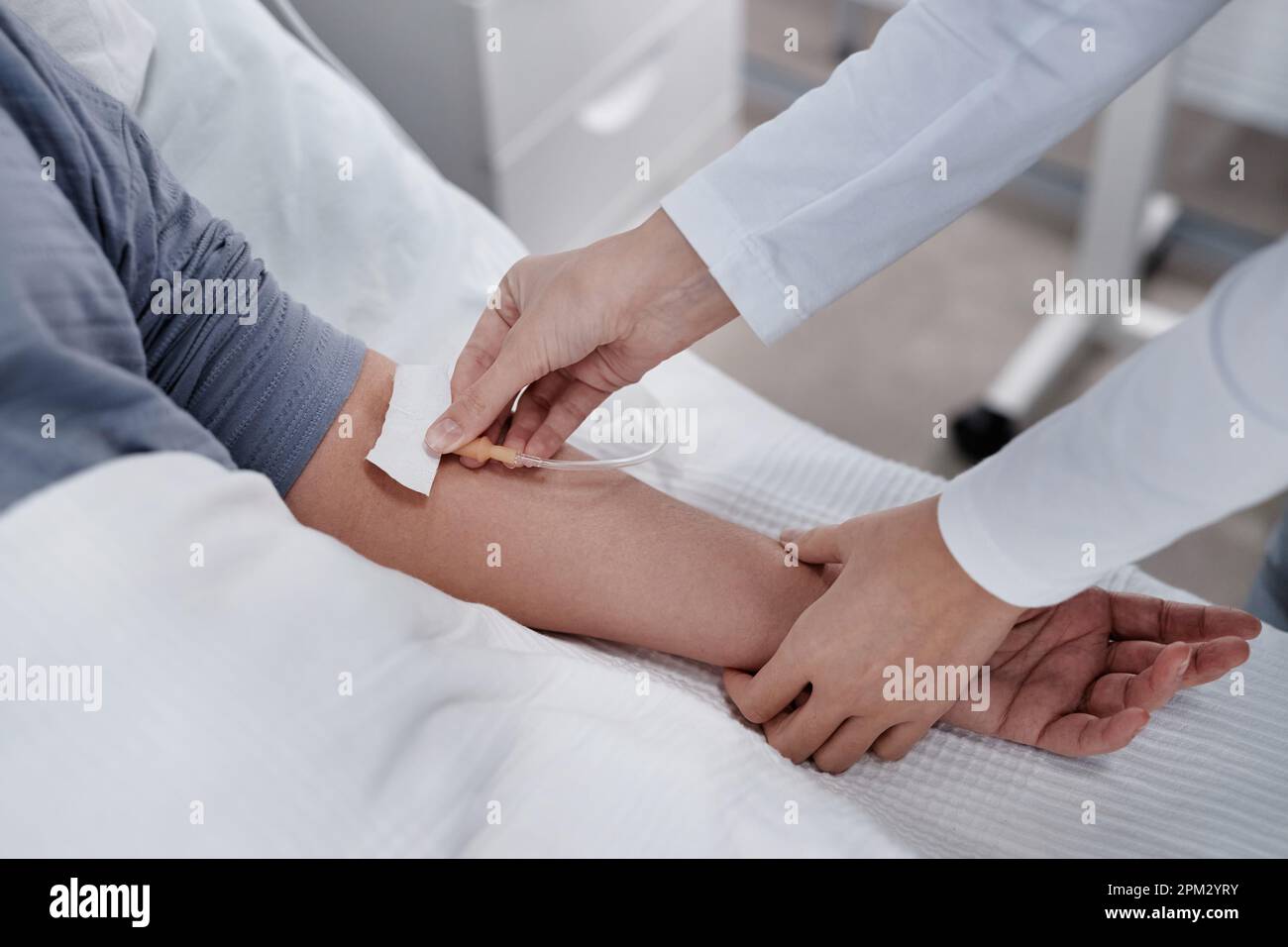 Close-up of doctor putting an IV drip to patient intravenously while ...