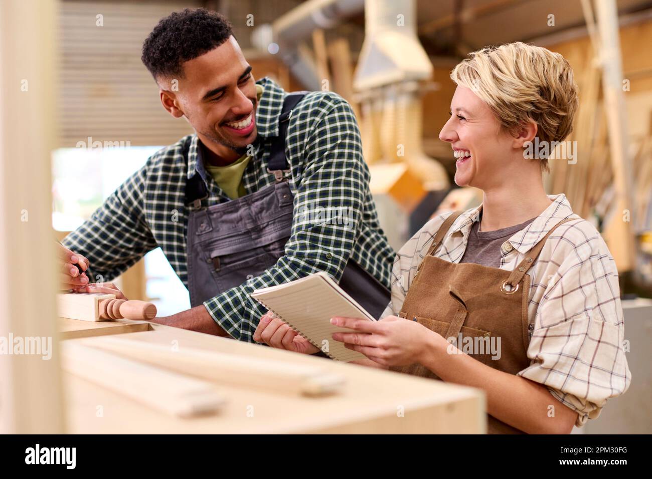 Male And Female Apprentices Working As Carpenters In Furniture Workshop ...