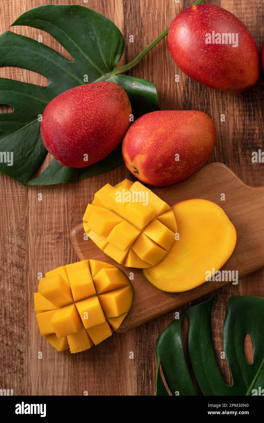 Top view of fresh ripe mango fruit with leaves over dark wooden table ...