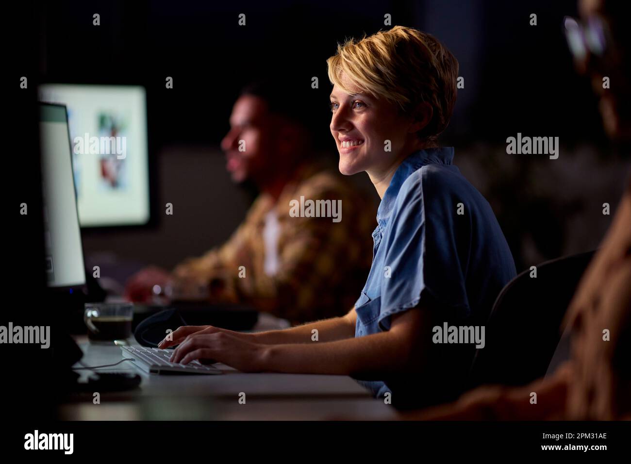 Business Team Using Computers At Desks In Office Working Late Stock ...