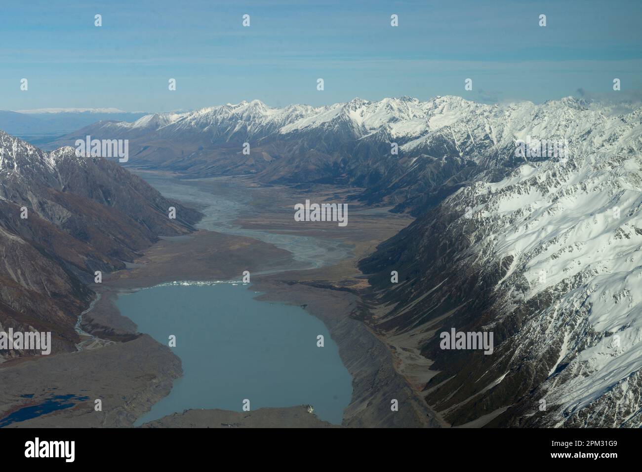 Tasman Lake, surrounded by outwash plain and snow-capped mountains ...