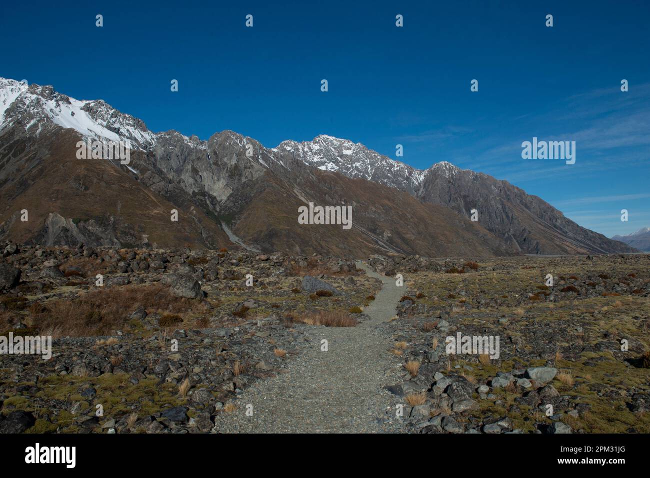 Path through across outwash plain, with snow-capped mountains in ...