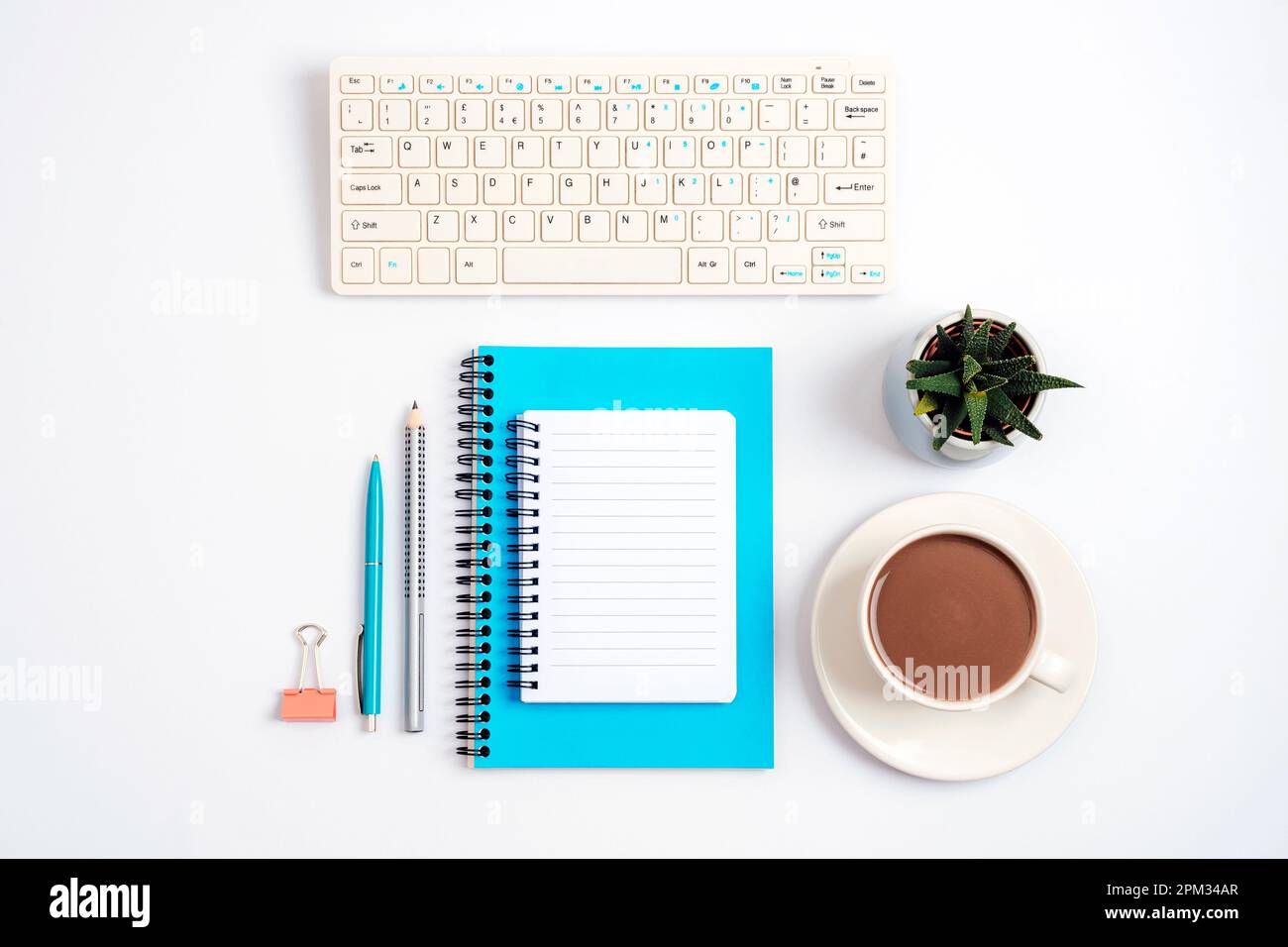 Workplace with computer keyboard, notepad, pen, pencil and cup of cocoa ...