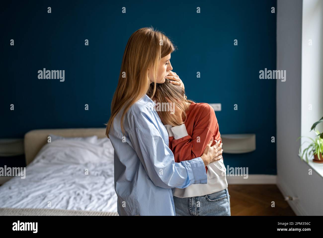 Mother hugging comforting upset crying teenage daughter at home ...