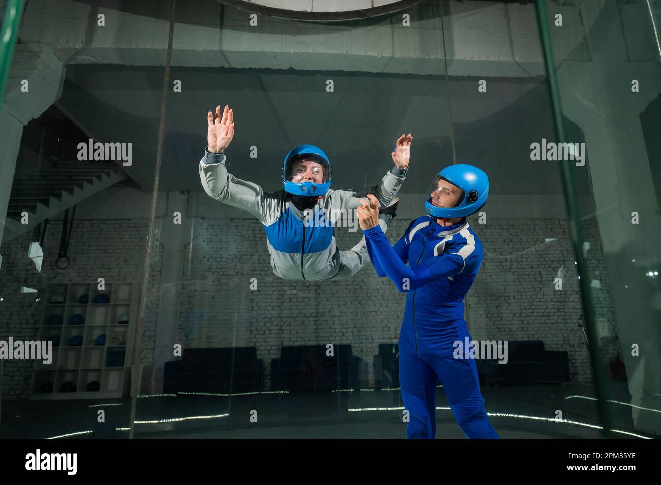 A male instructor teaches a woman how to fly in a wind tunnel. Free ...