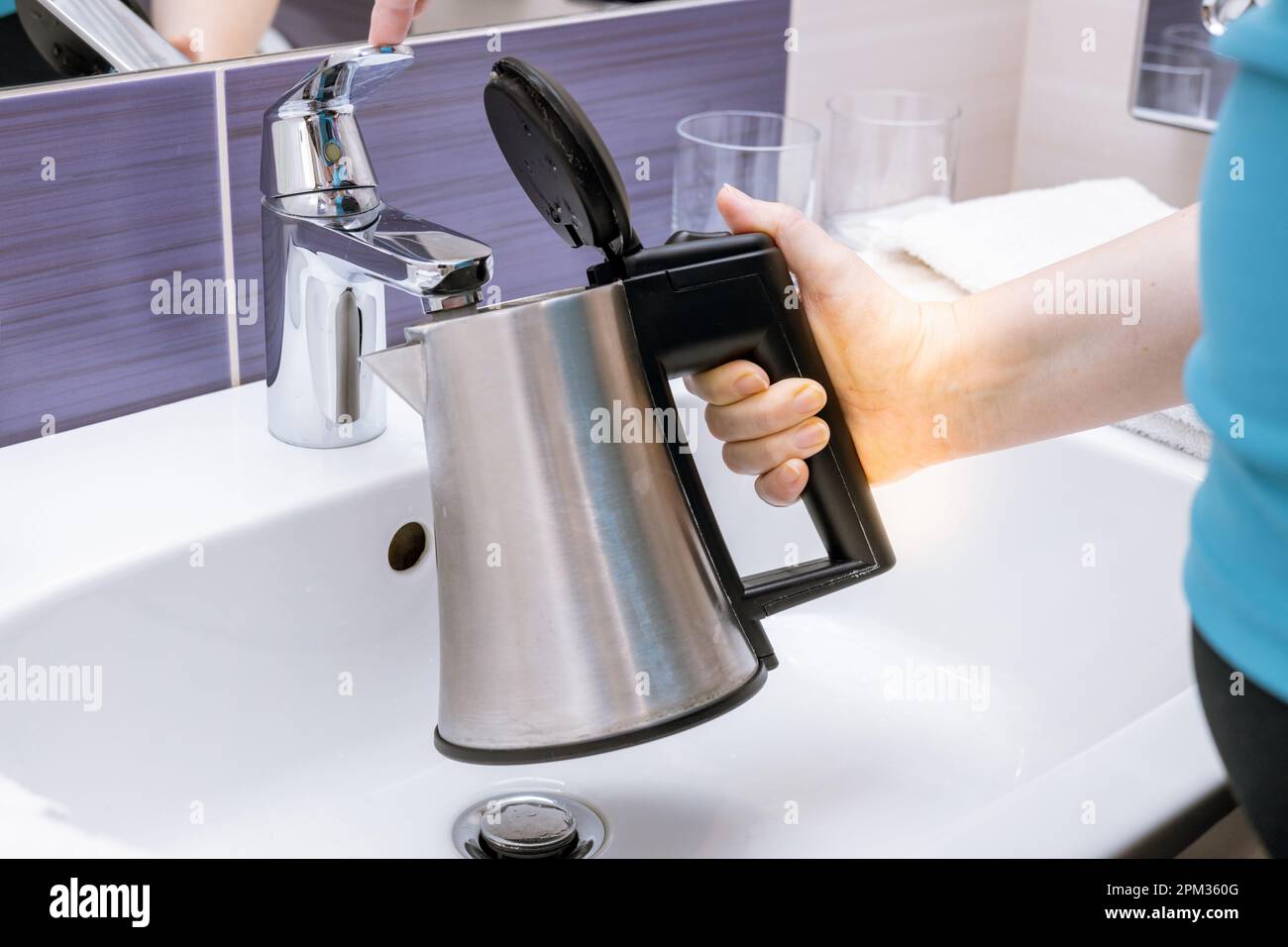 A woman pours water into a kettle in a hotel sink Stock Photo - Alamy