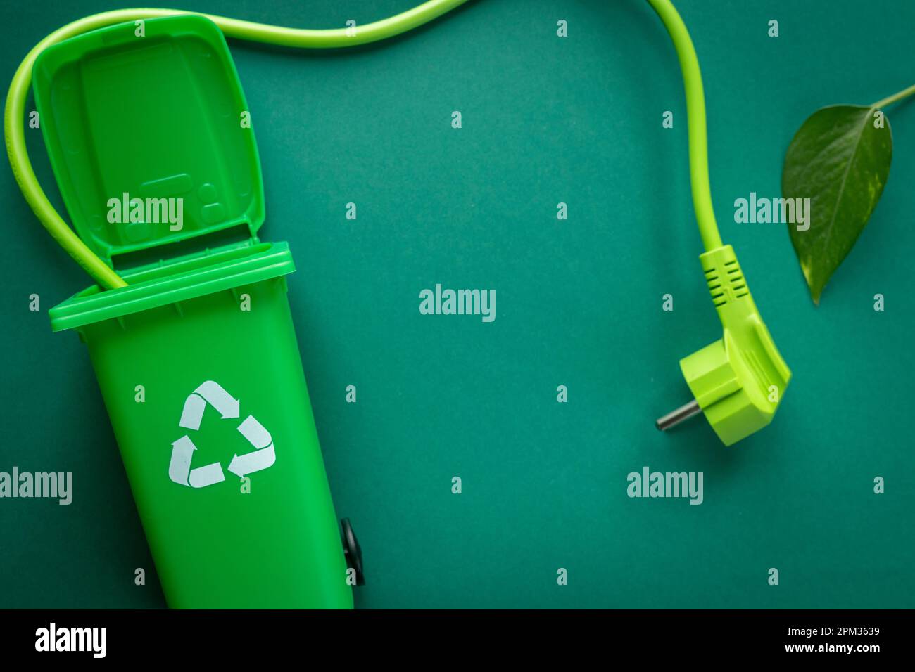 Green cable sticking out of a recycling bin, Environmental concept ...
