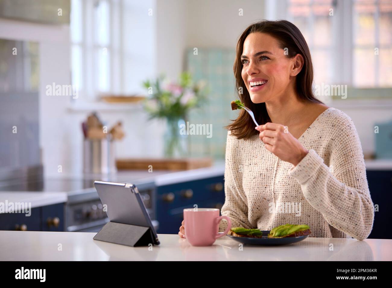 Woman At Home With Digital Tablet On Kitchen Counter Eating Lunch Stock ...