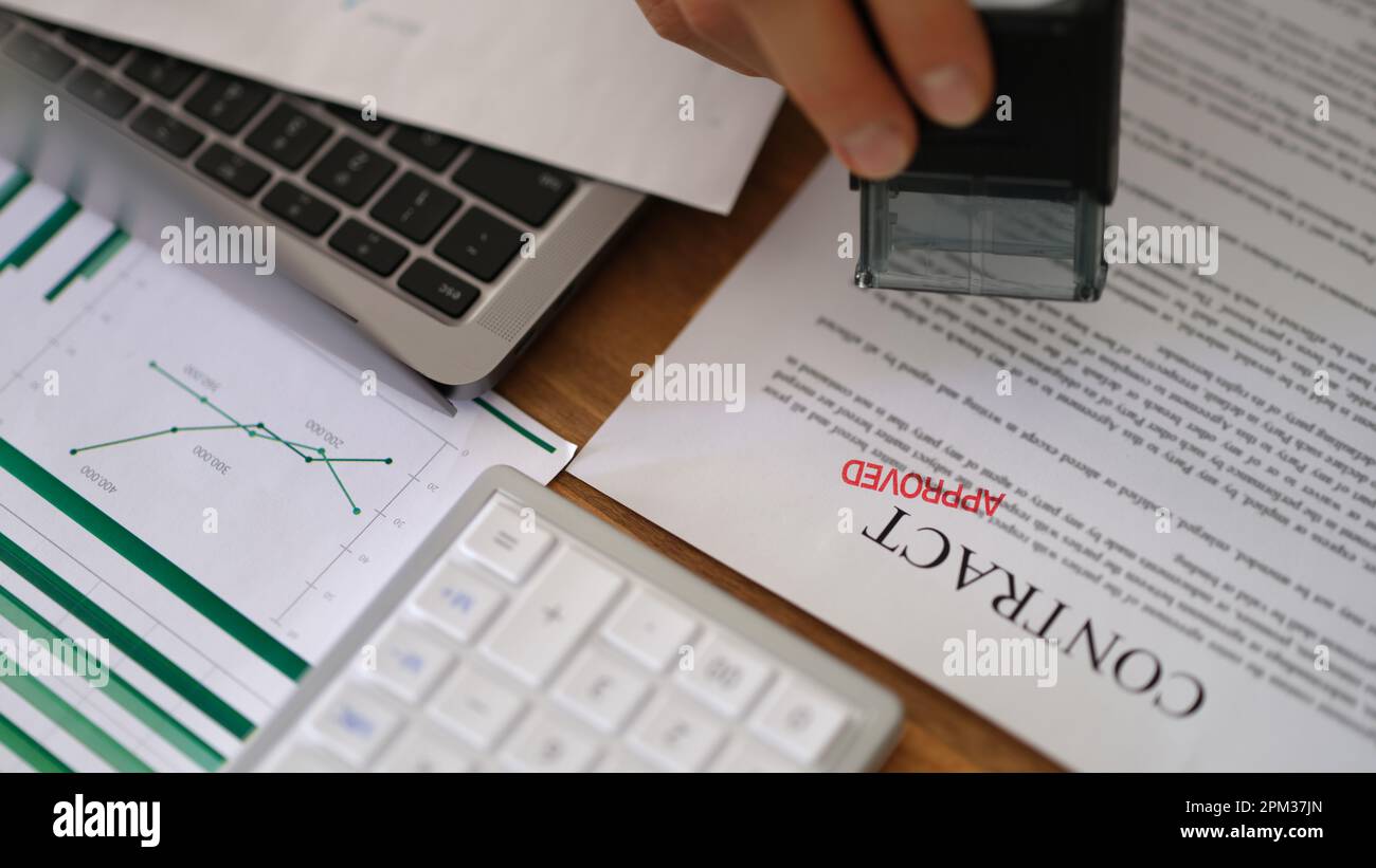 Manager hand putting stamp approved on contract document form in office ...