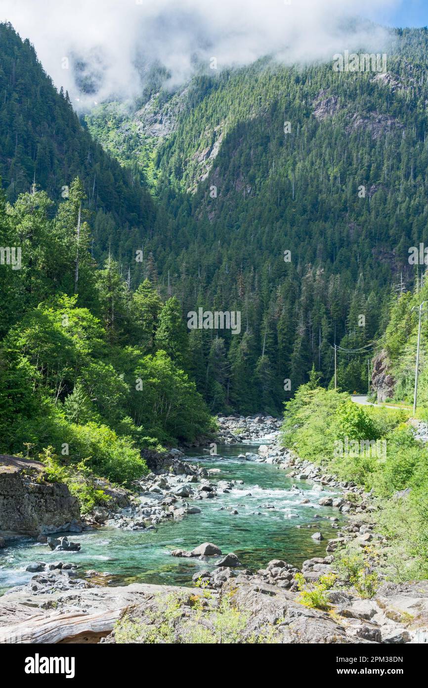 Mountain landscape with asphalt road and shallow river running through ...