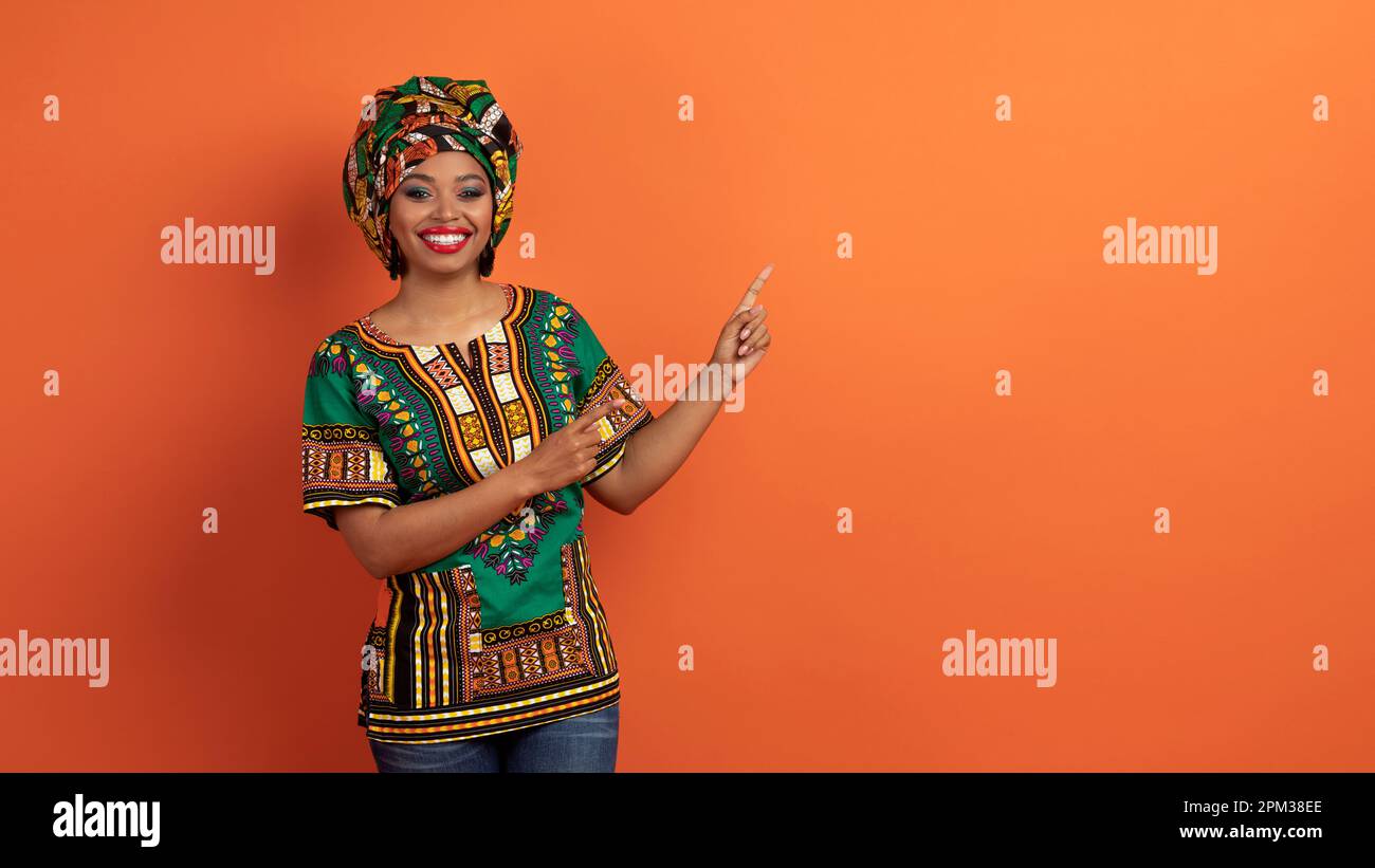 Pretty black woman in african costume pointing at free space Stock ...