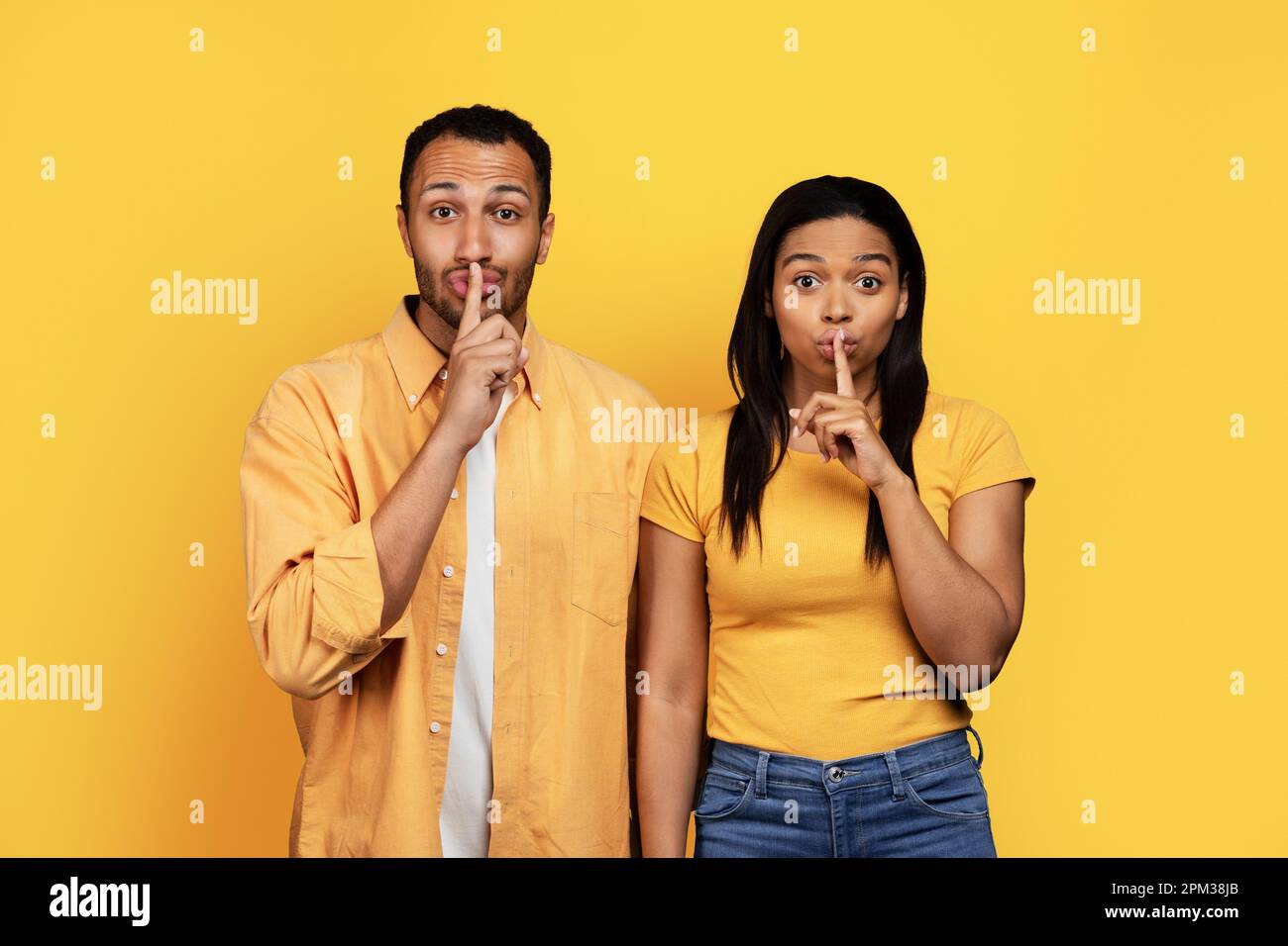 Millennial african american guy and female putting finger to mouth ...