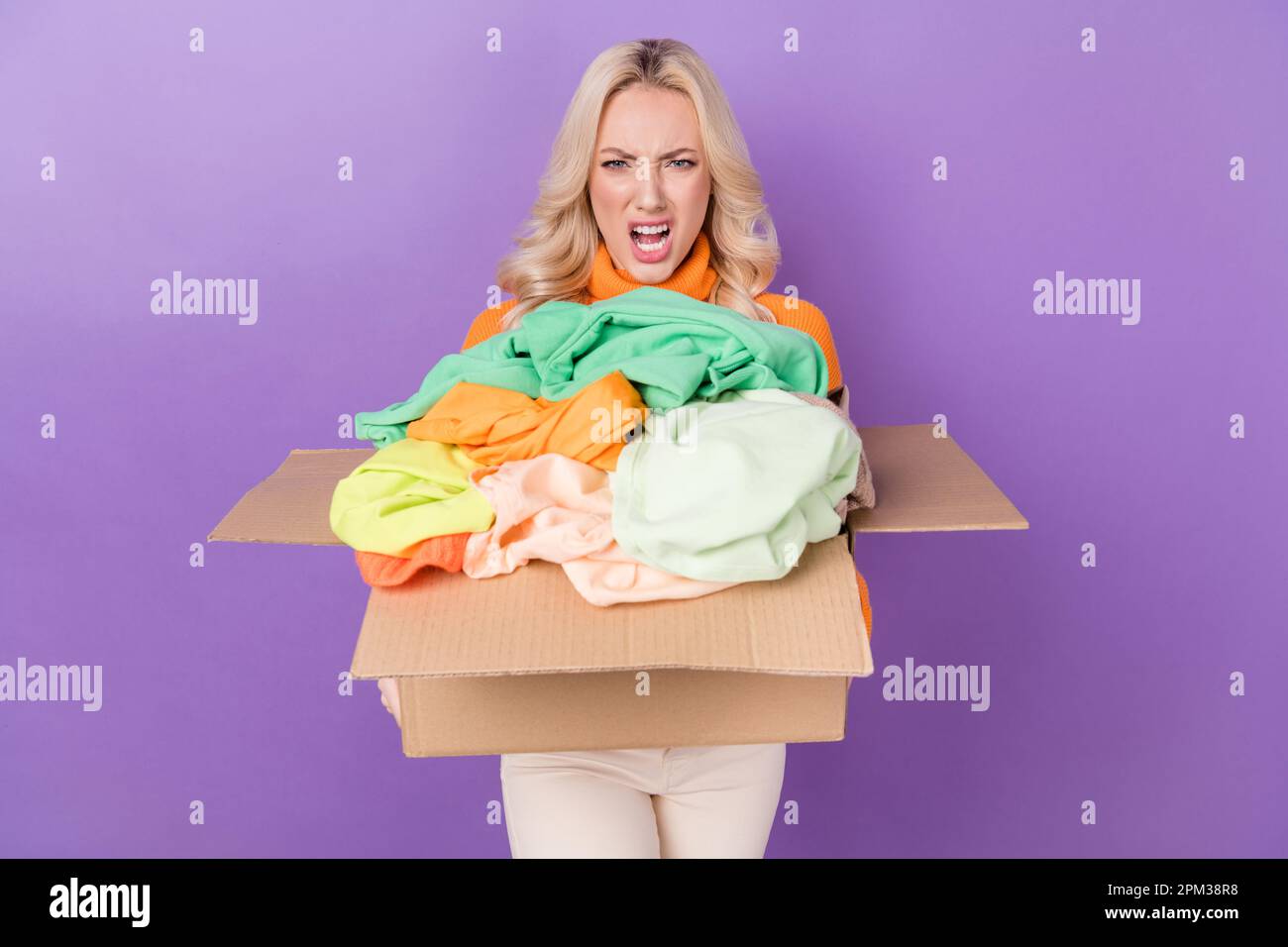 Portrait of unsatisfied aggressive lady hold pile stack clothes box ...