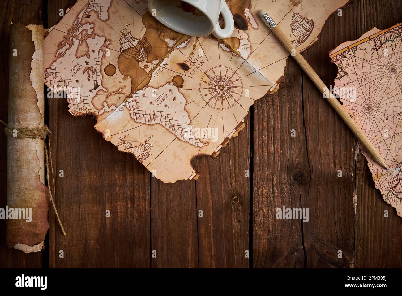 An aged parchment scroll with old maps and a spilled coffee cup on a ...