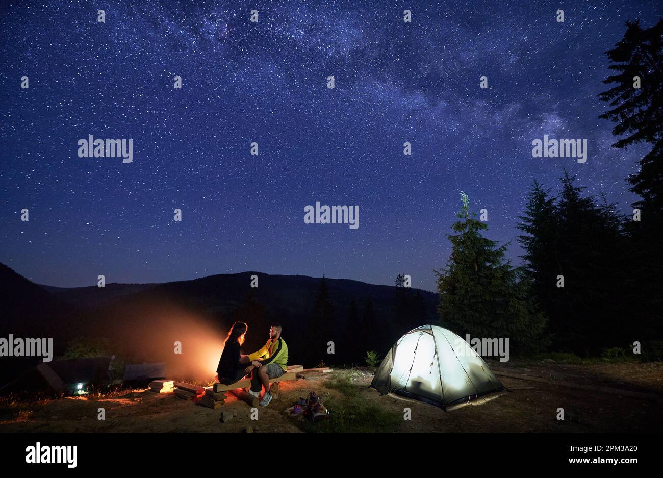 Nocturnal camping experience in mountains under stars. Man and woman ...