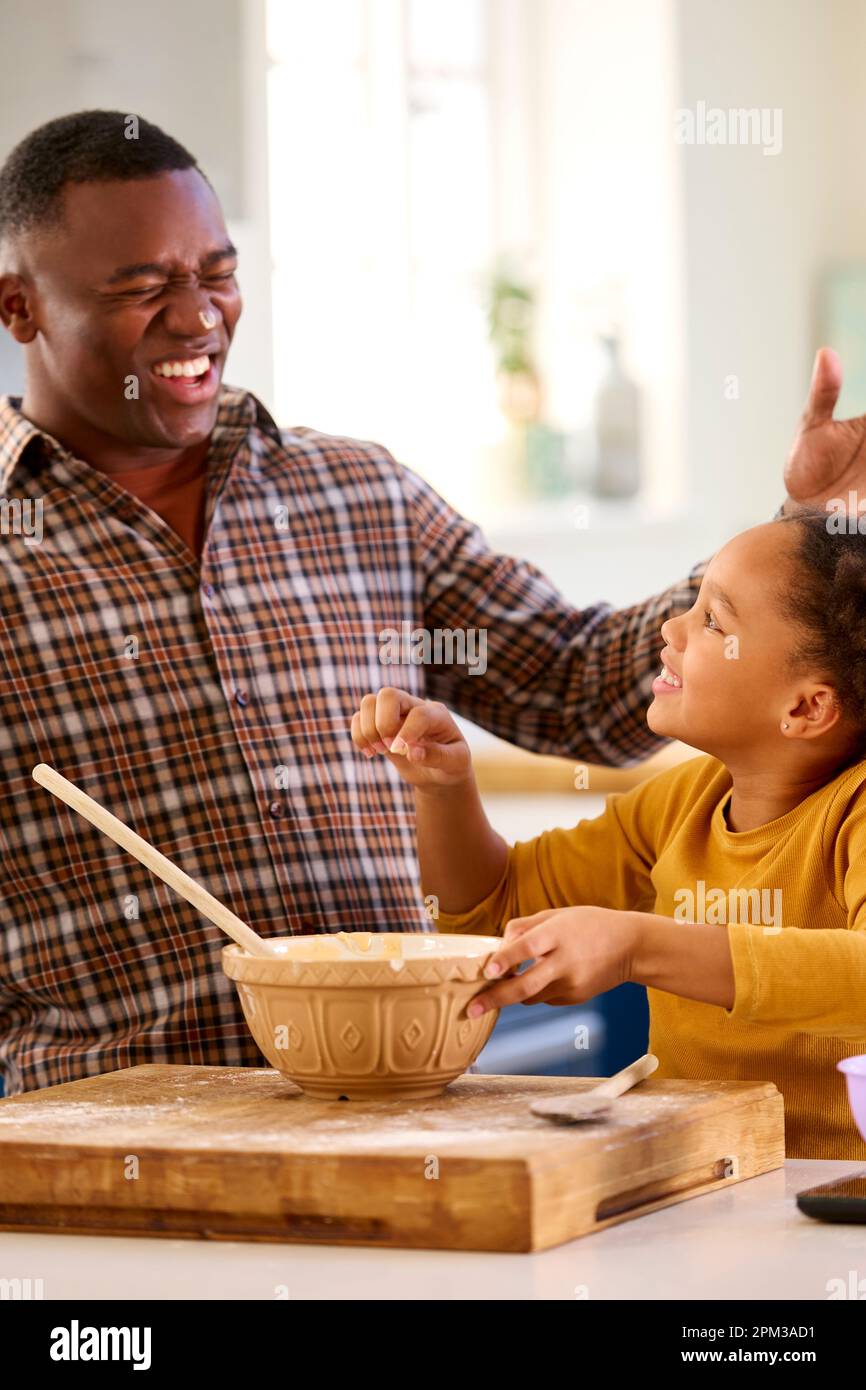Family Shot With Father And Daughter Having Messy Fun Baking At Home In ...