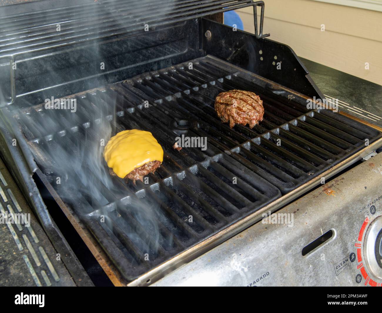 Hamburger and cheeseburger grilling on an outdoor gas grill in ...