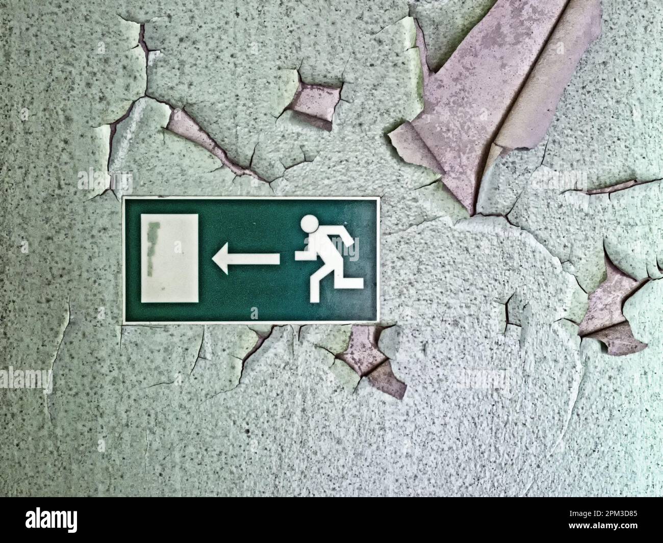 Emergency exit sign in old building on wall with peeling paint Stock ...