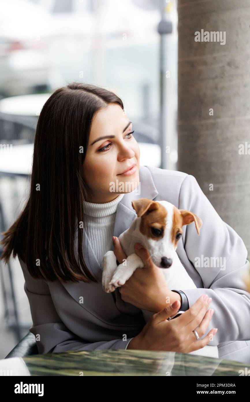 Caucasian woman and jack russell terrier look at the cake with a candle ...
