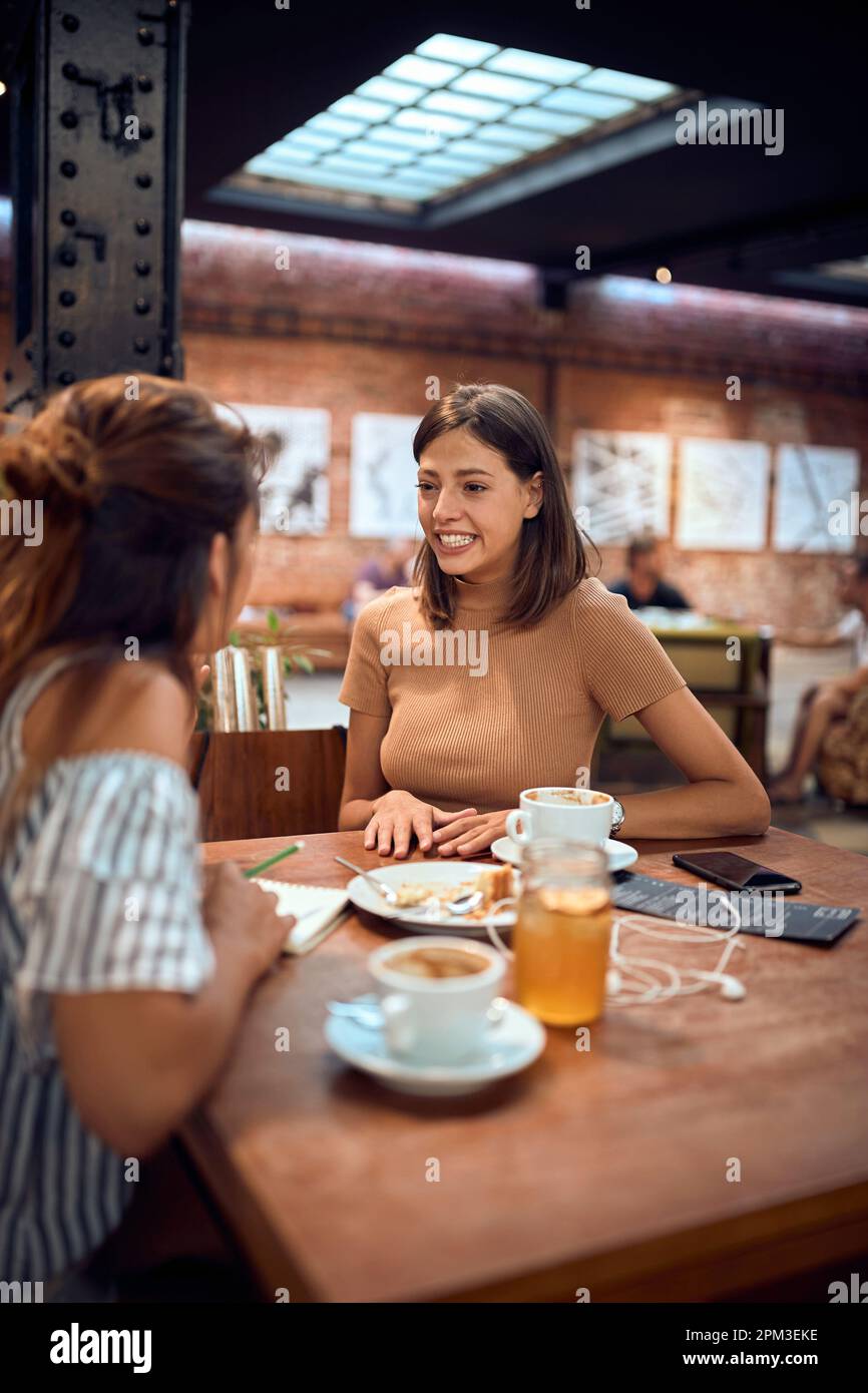 Young grilfriends at cafe having a chat and enjoying coffee time ...
