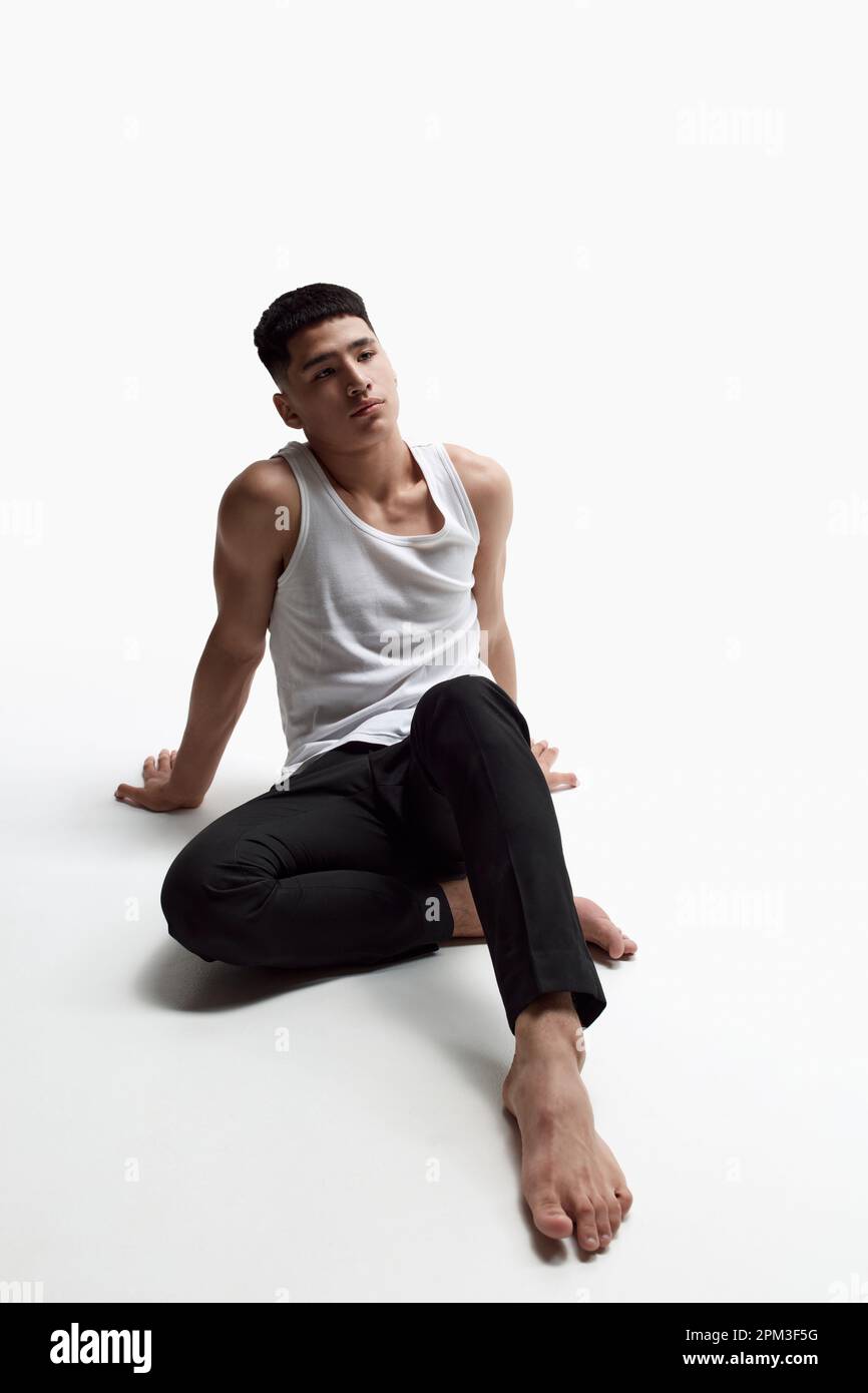 Portrait of young handsome man posing in black trousers and singlet ...