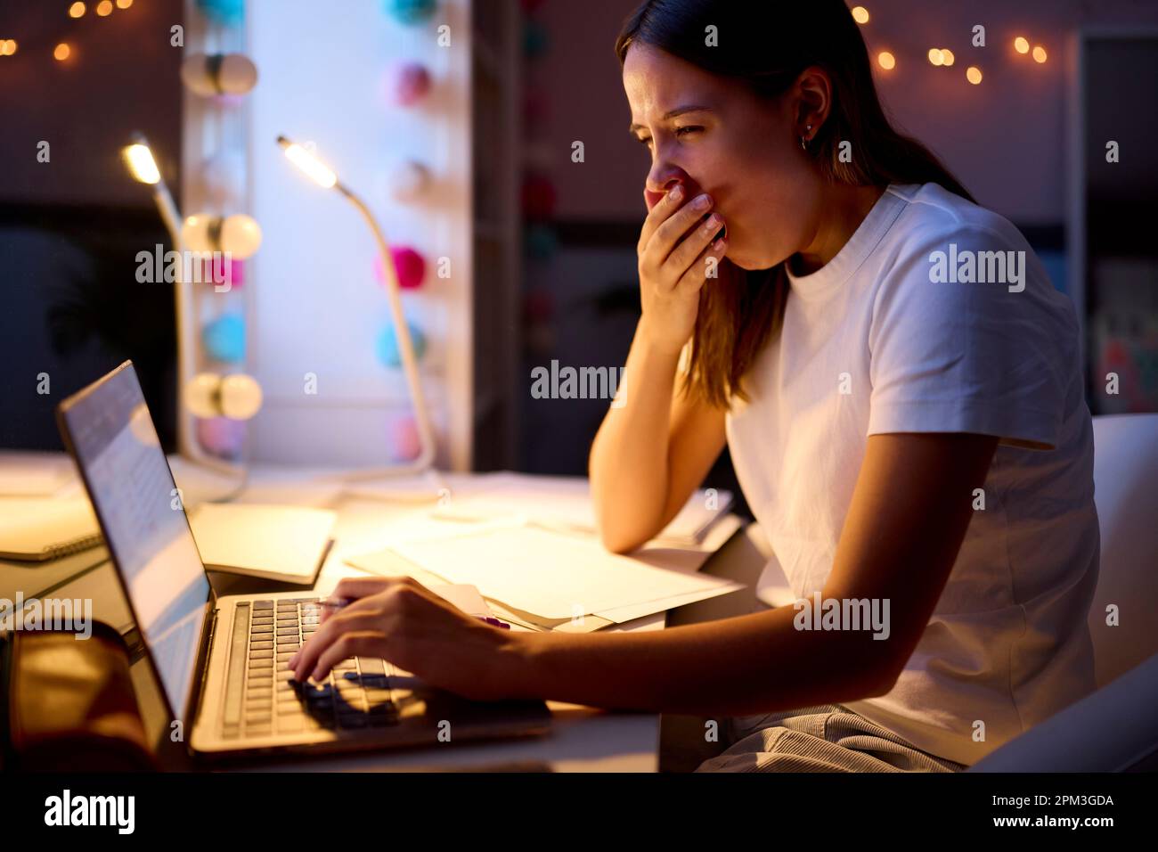 Tired Teenage Girl Yawning Studying At Home With Laptop In Bedroom Desk ...