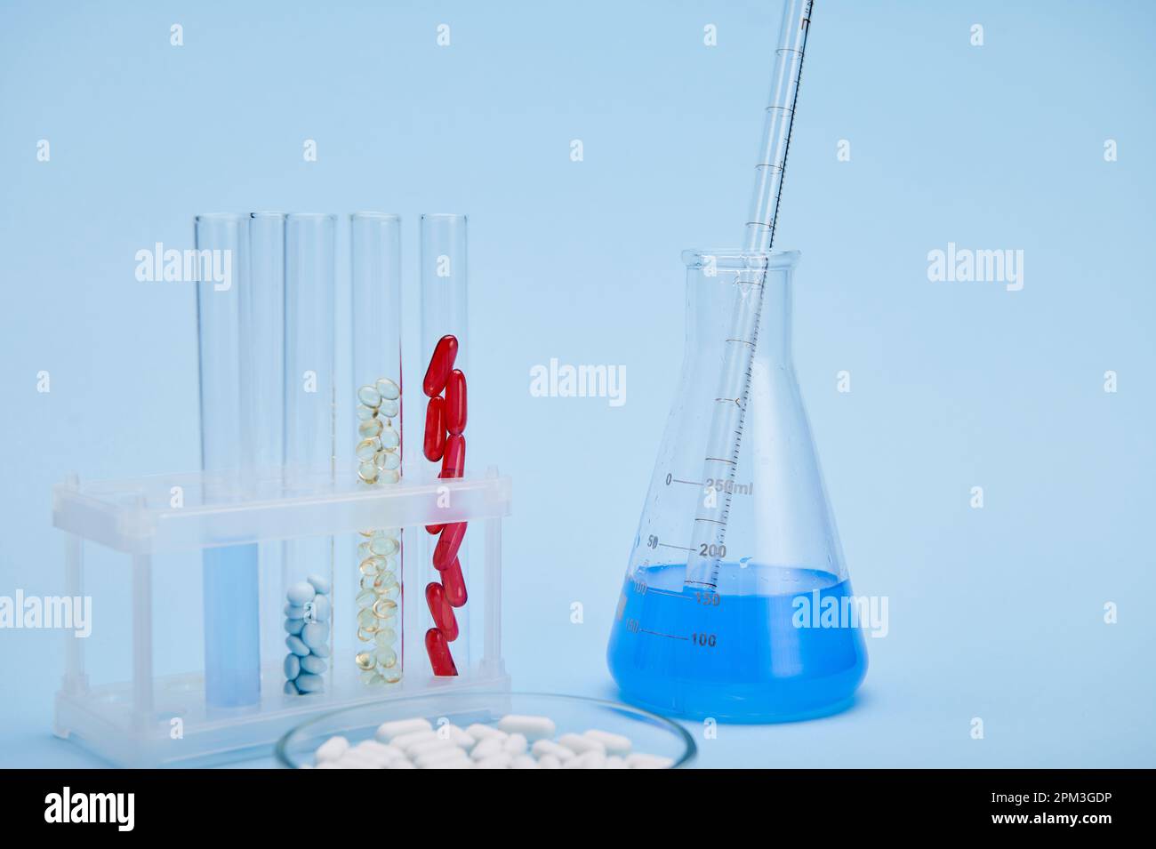 Test tubes with gelatin capsules, petri dish with pills and graduated ...