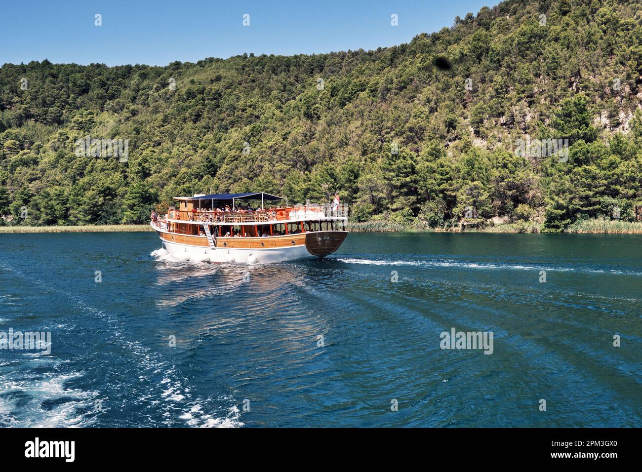 A boat cruising through a tranquil lake in Krka National Park, Croatia ...