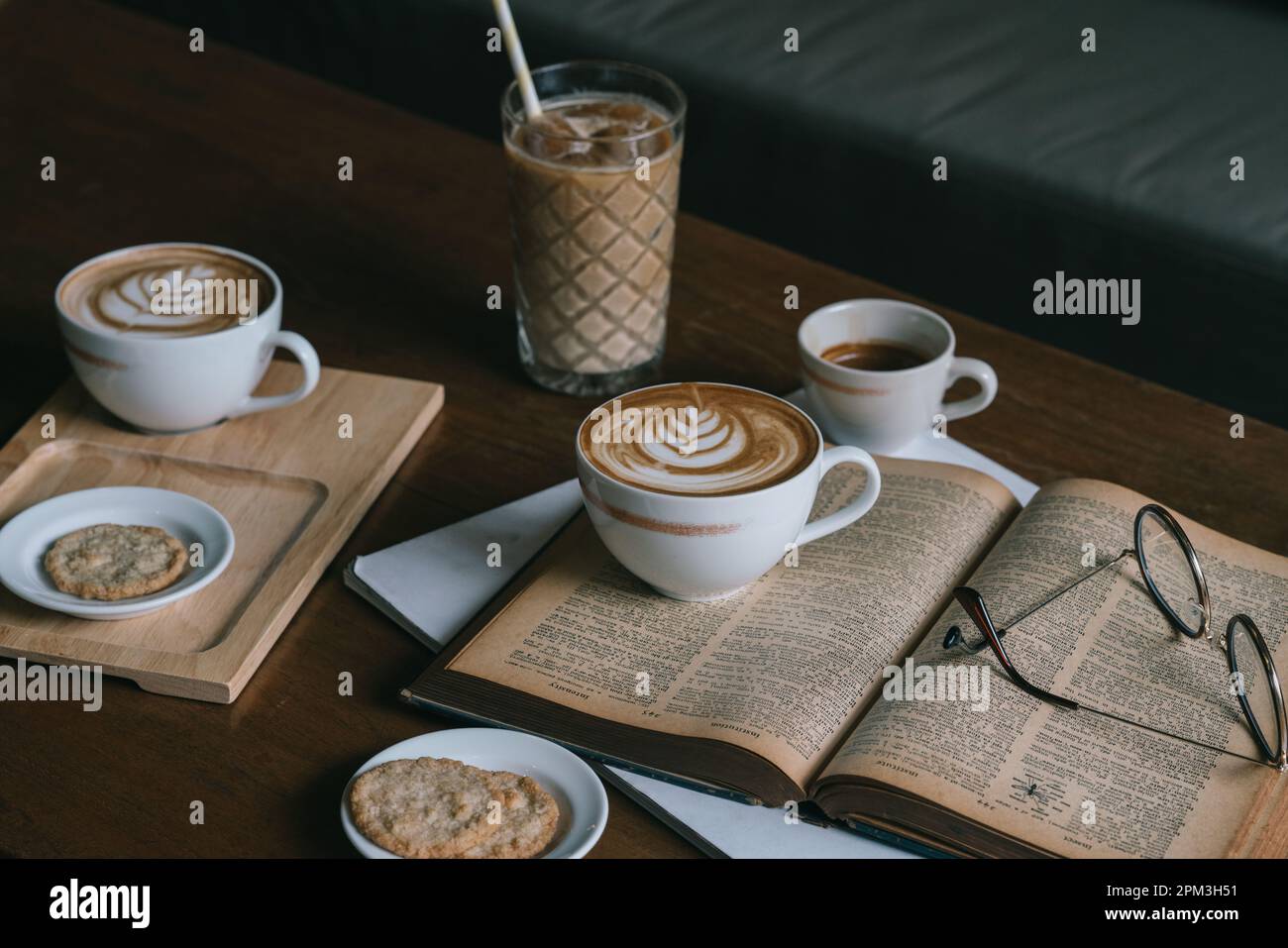 A moody close-up of a selection of coffee cups and cookies next to a ...