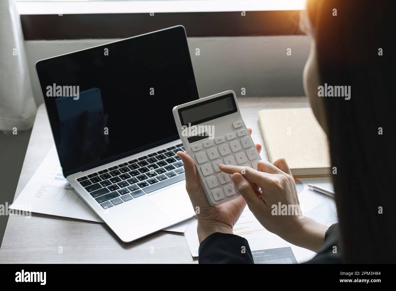 Bookkeeper using a calculator to calculate numbers on a company's ...