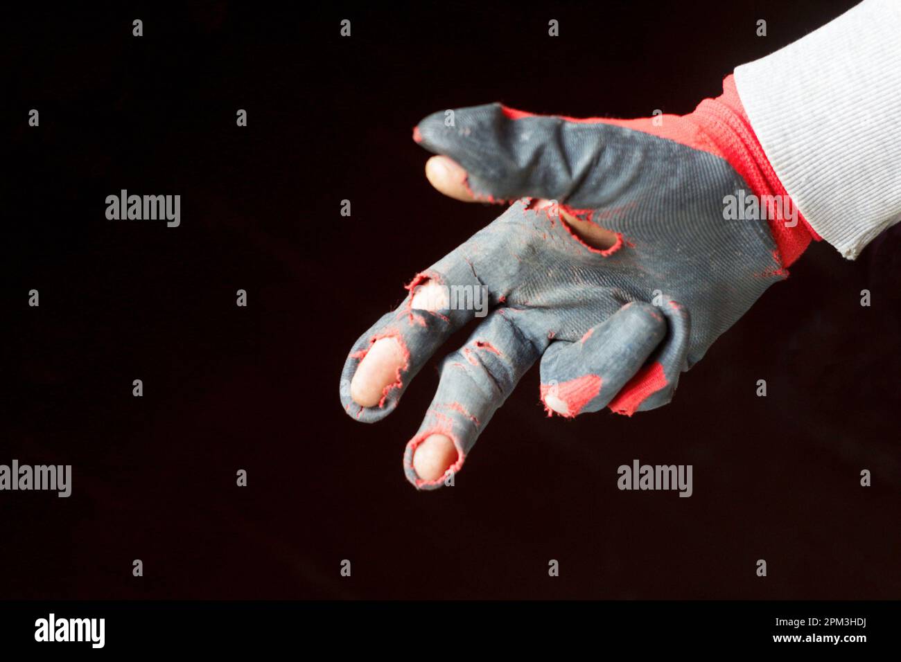 Demaged glove. Defocus worn dirty and leaky gloves. One male hand in ...