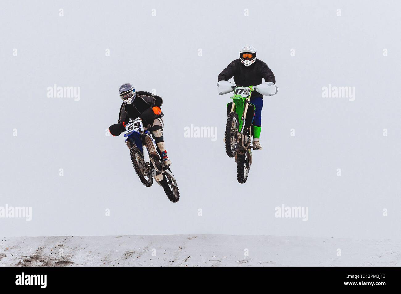two motocross rider jumping together on snowy springboard, winter off ...