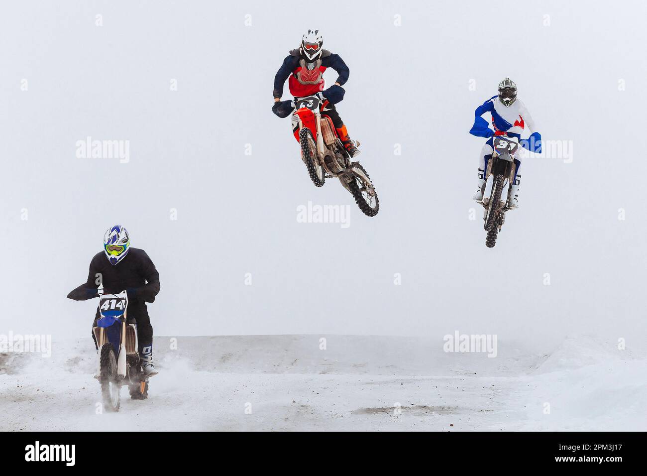 group motorsport rider jumping together on snowy springboard, winter ...