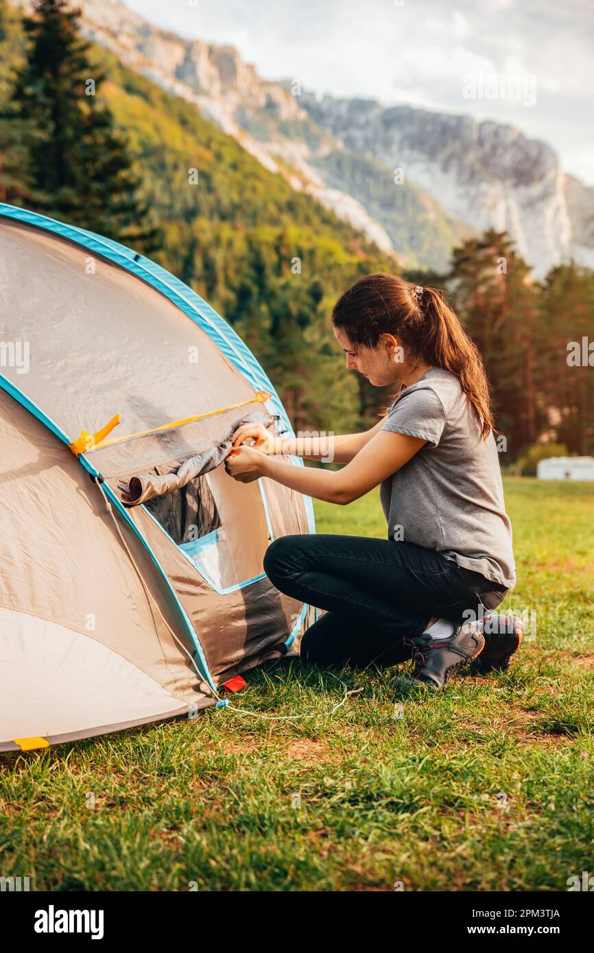Young woman setting up a tent in amazing landscape of forest and ...