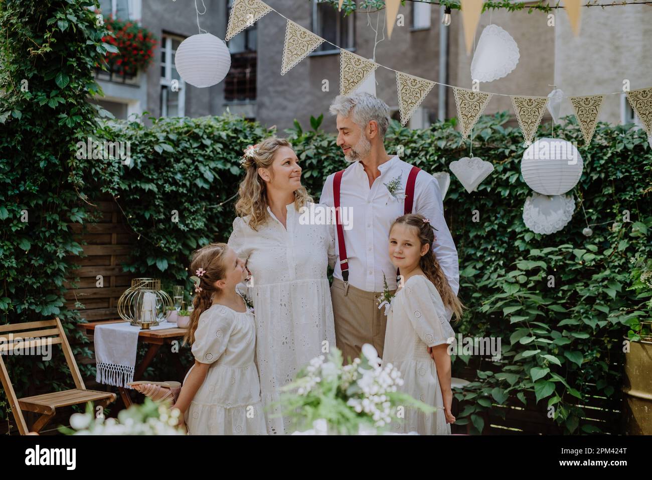 Mature bride and groom posing with their daughters at wedding reception ...