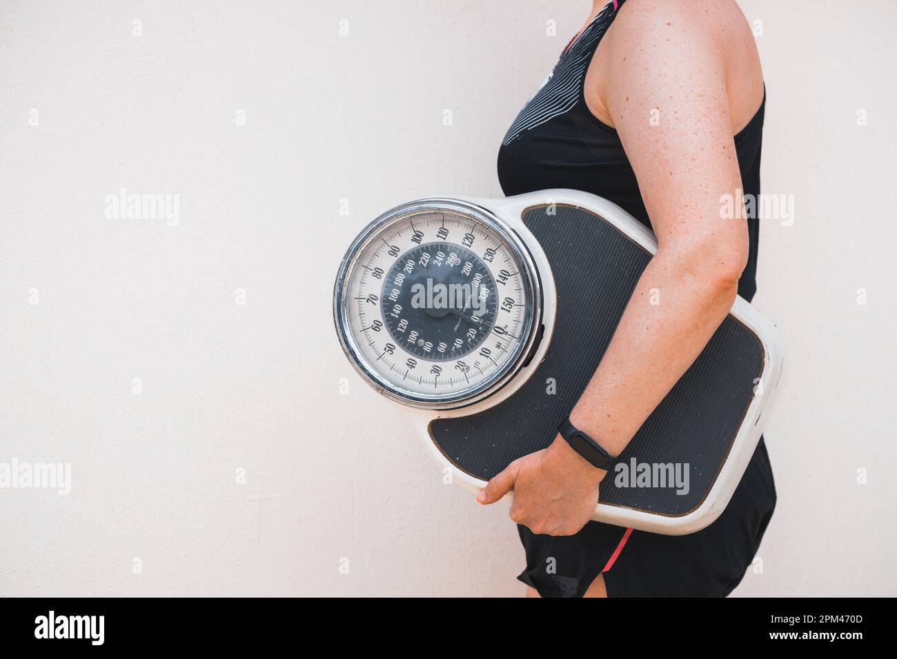 A woman in a sports outfit holds a professional scale under her arm ...